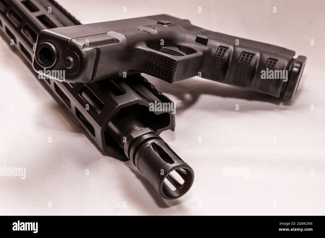 A black 9mm pistol on top of a black AR 15 .223 caliber rifle with a ...