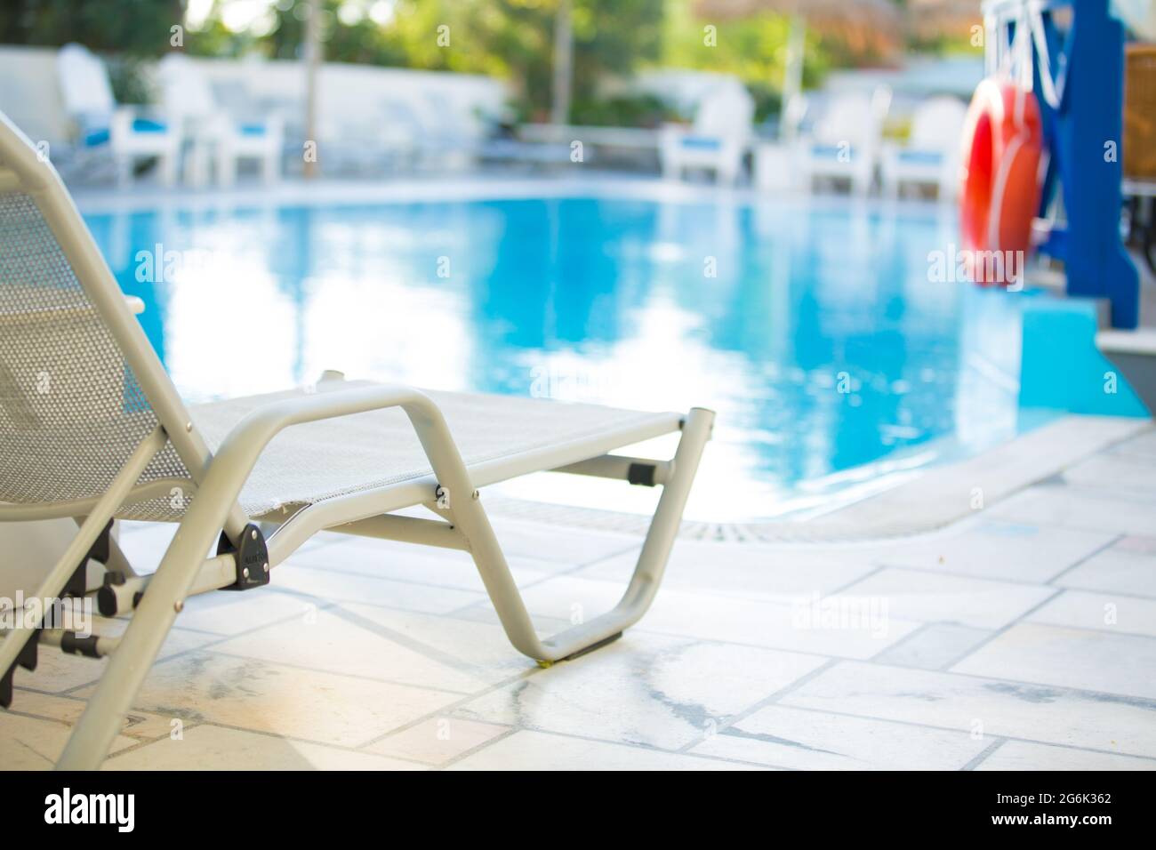 Sun loungers by the pool with water next to the hotel Stock Photo - Alamy