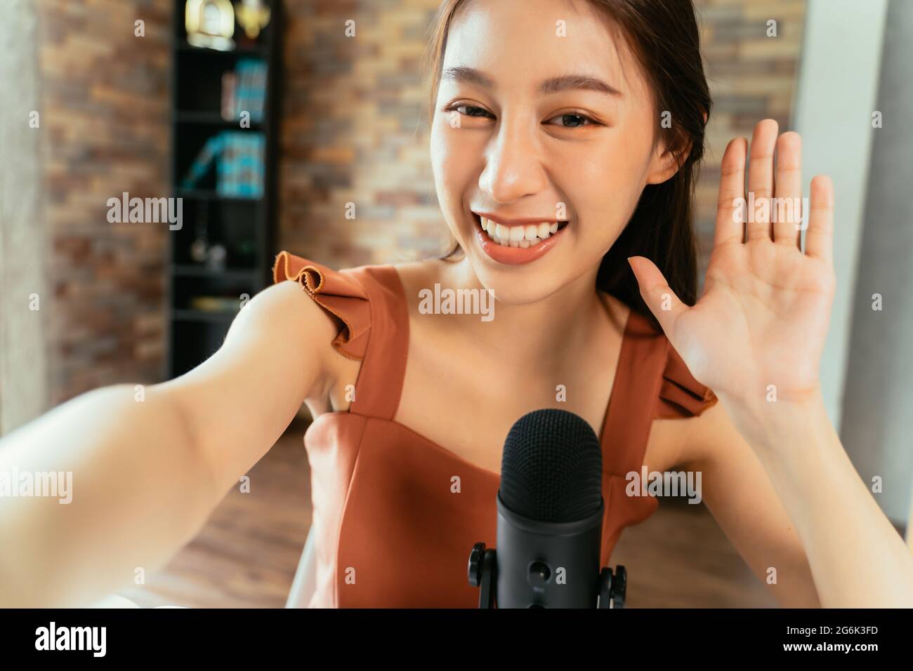 Portrait of cheerful young Asian female blogger using mic and laptop ...