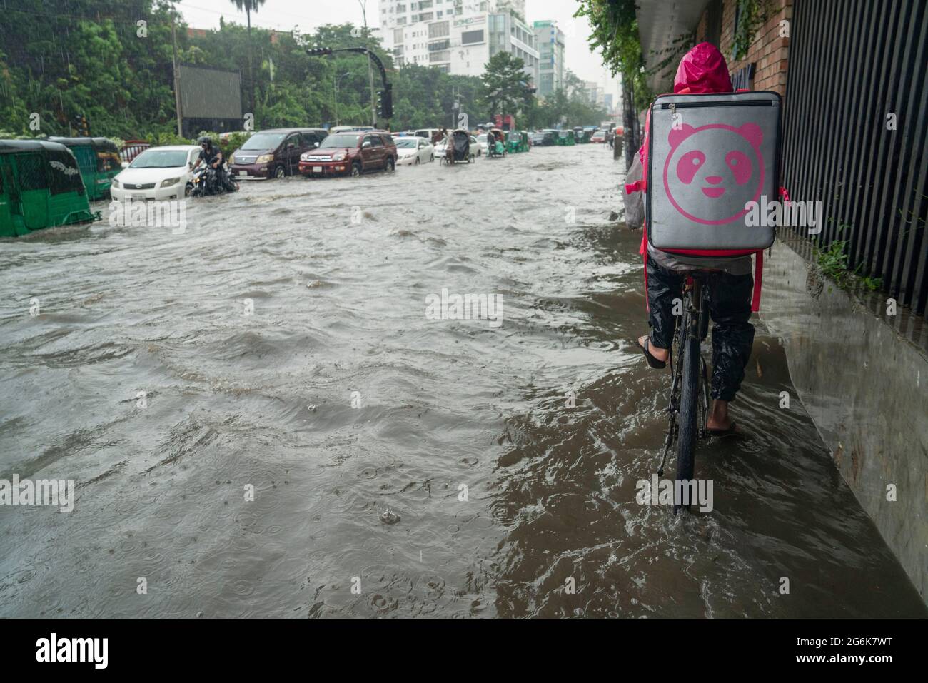 A man delivering food rides through rain water on his bicycle along ...