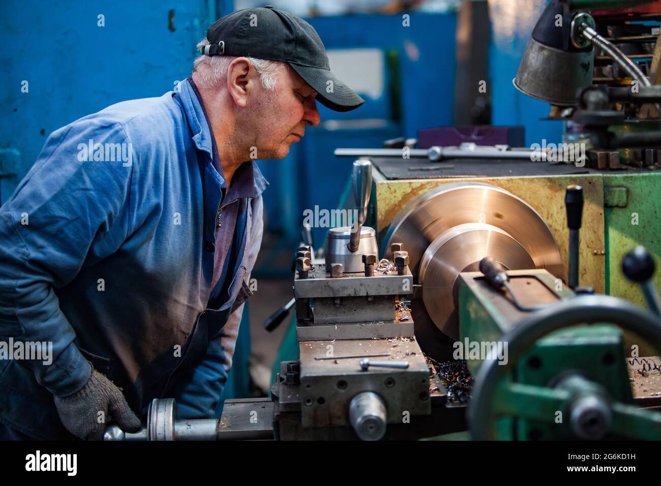 Turning lathe operator at work. Adult caucasian man machining steel ...