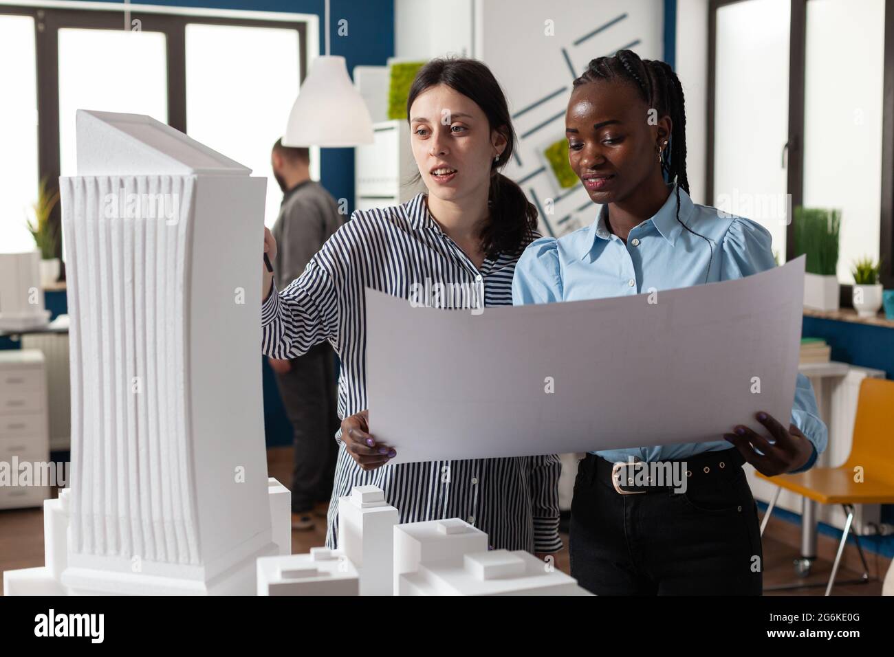 Colleagues architects women checking plans of blueprints layout design ...