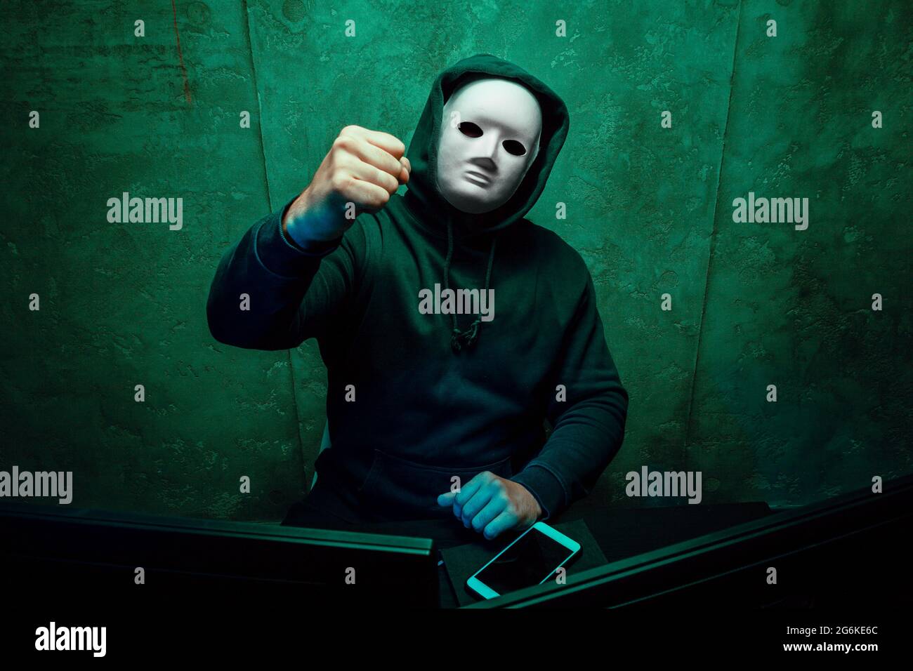 Anonymous hacker wearing face mask working on computer in dark room ...