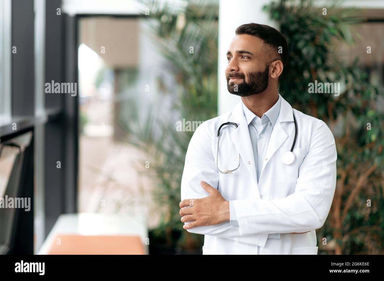 Indian handsome confident general medicine doctor, stands in a clinic ...