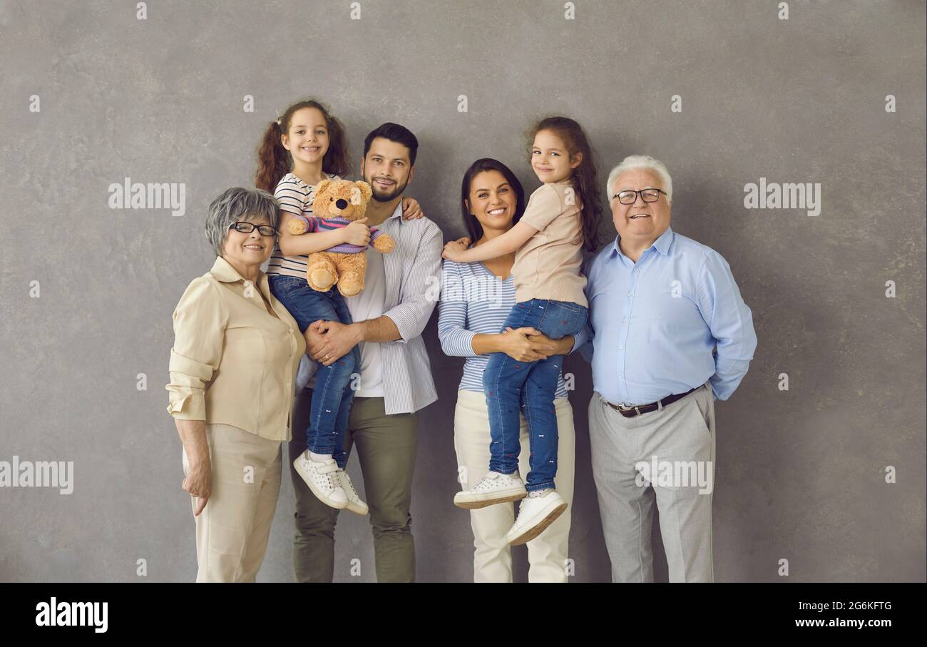 Studio portrait of happy mom, dad, kids and grandparents standing ...