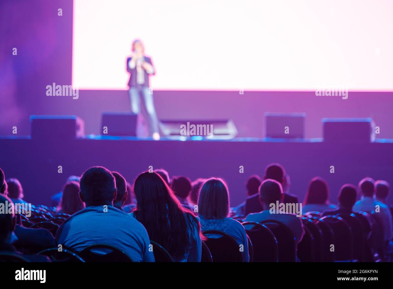 Audience listening to speaker in neon light Stock Photo - Alamy