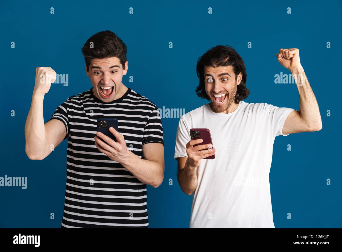 Excited two men making winner gesture while using cellphones isolated ...