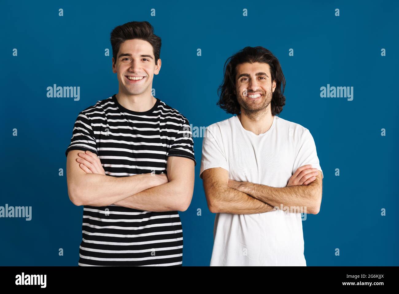 White brunette two men looking and smiling at camera isolated over blue ...