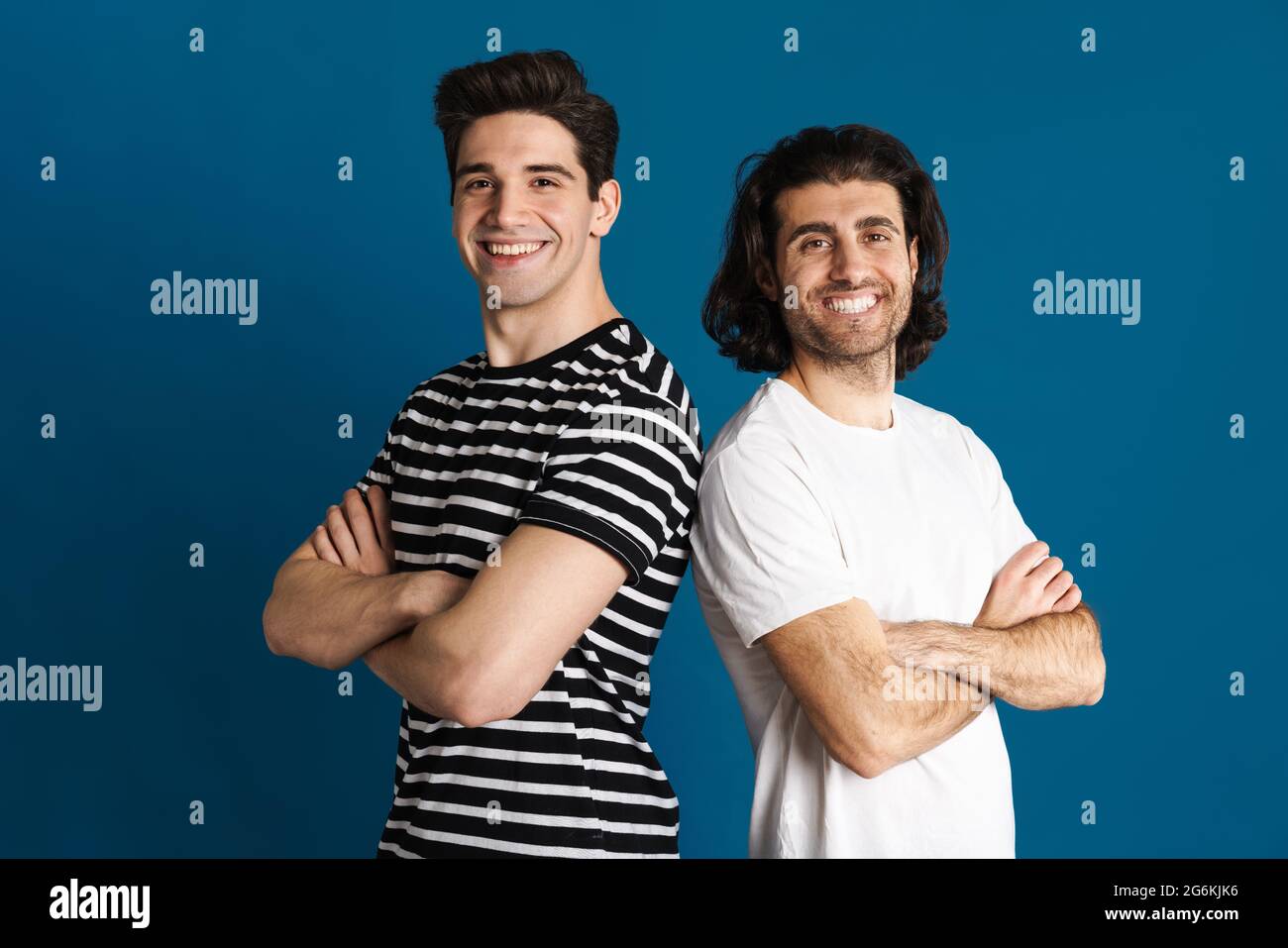 White brunette two men looking and smiling at camera isolated over blue ...