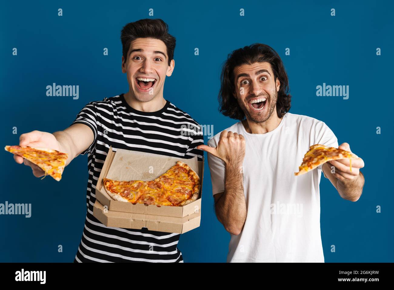 Excited two men screaming and posing with pizza isolated over blue ...