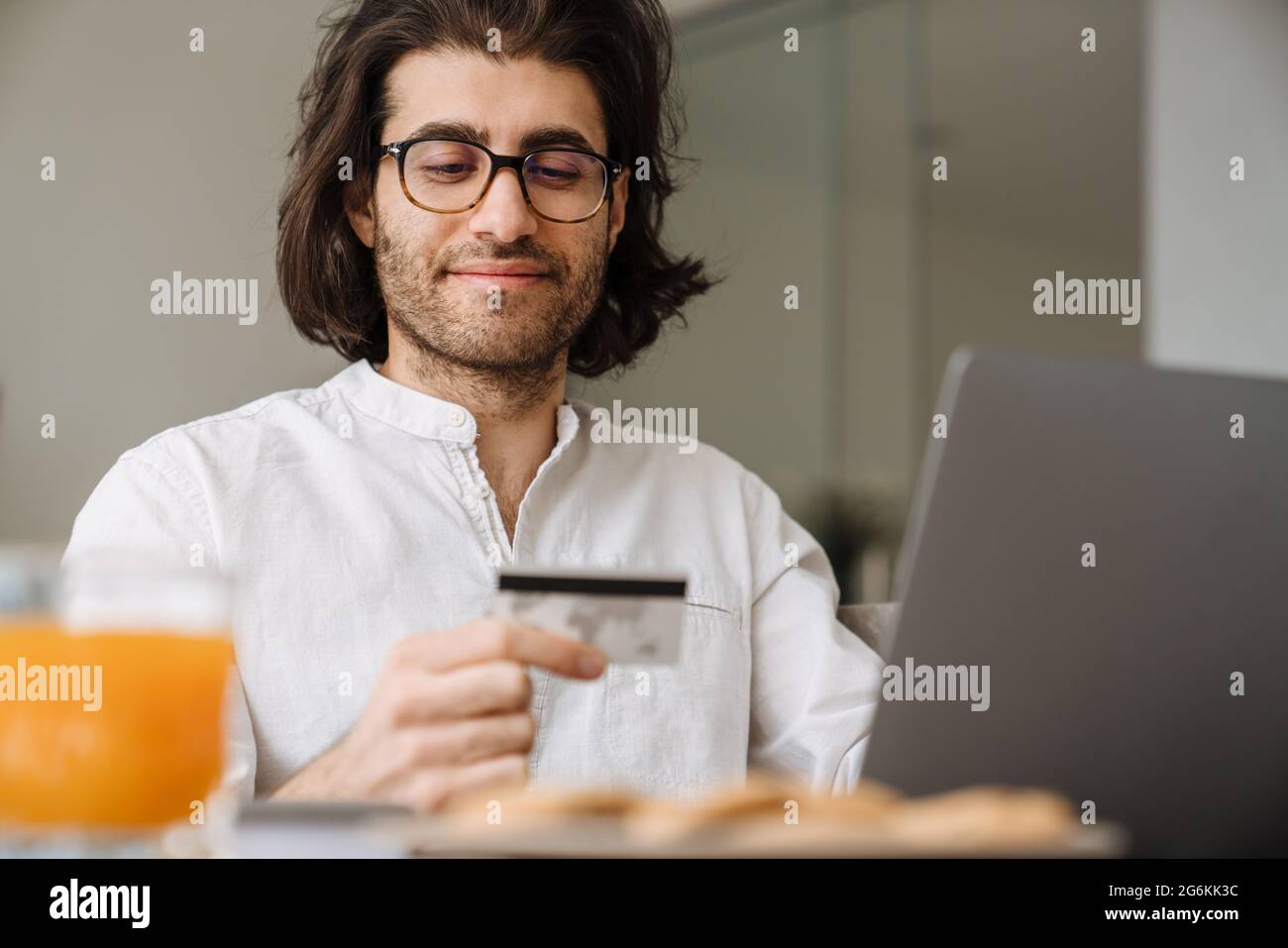 Smiling mid aged brunette turkish man sitting at the table with laptop ...