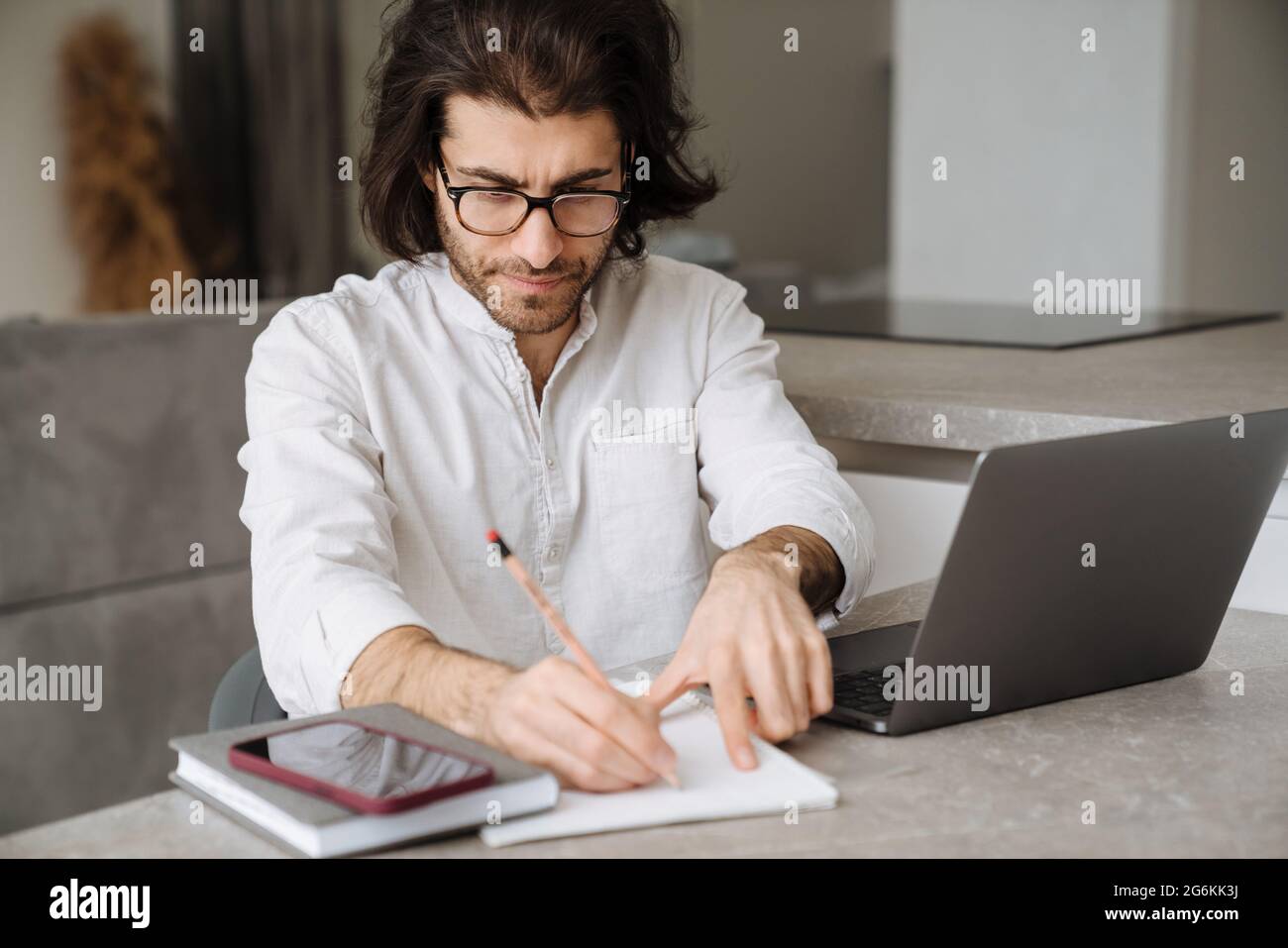 Pensive mid aged brunette turkish man sitting at the table with laptop ...