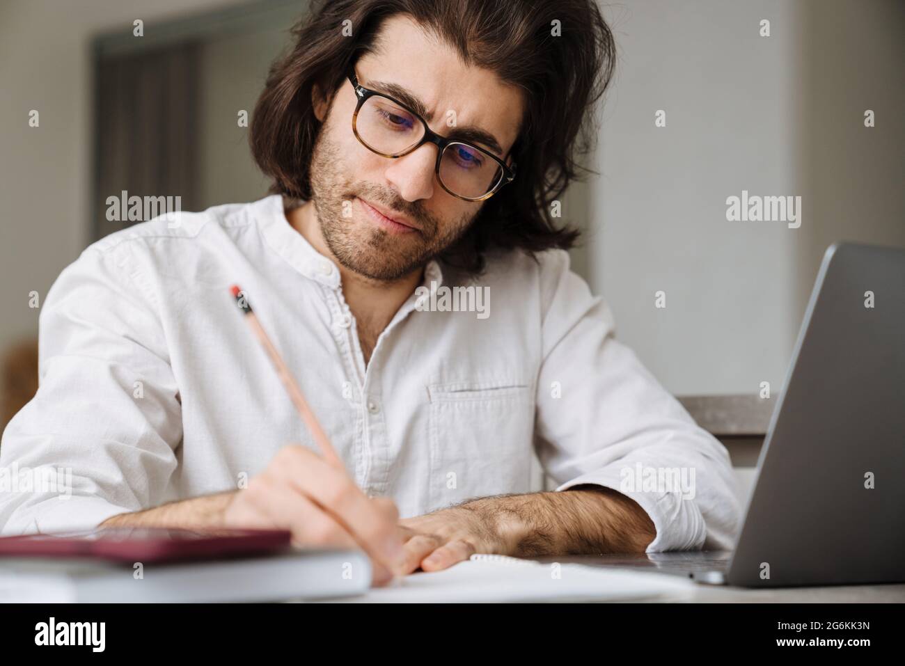 Pensive mid aged brunette turkish man sitting at the table with laptop ...