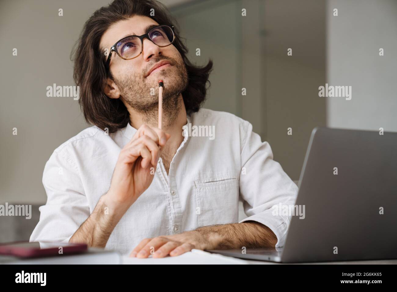 Pensive mid aged brunette turkish man sitting at the table with laptop ...