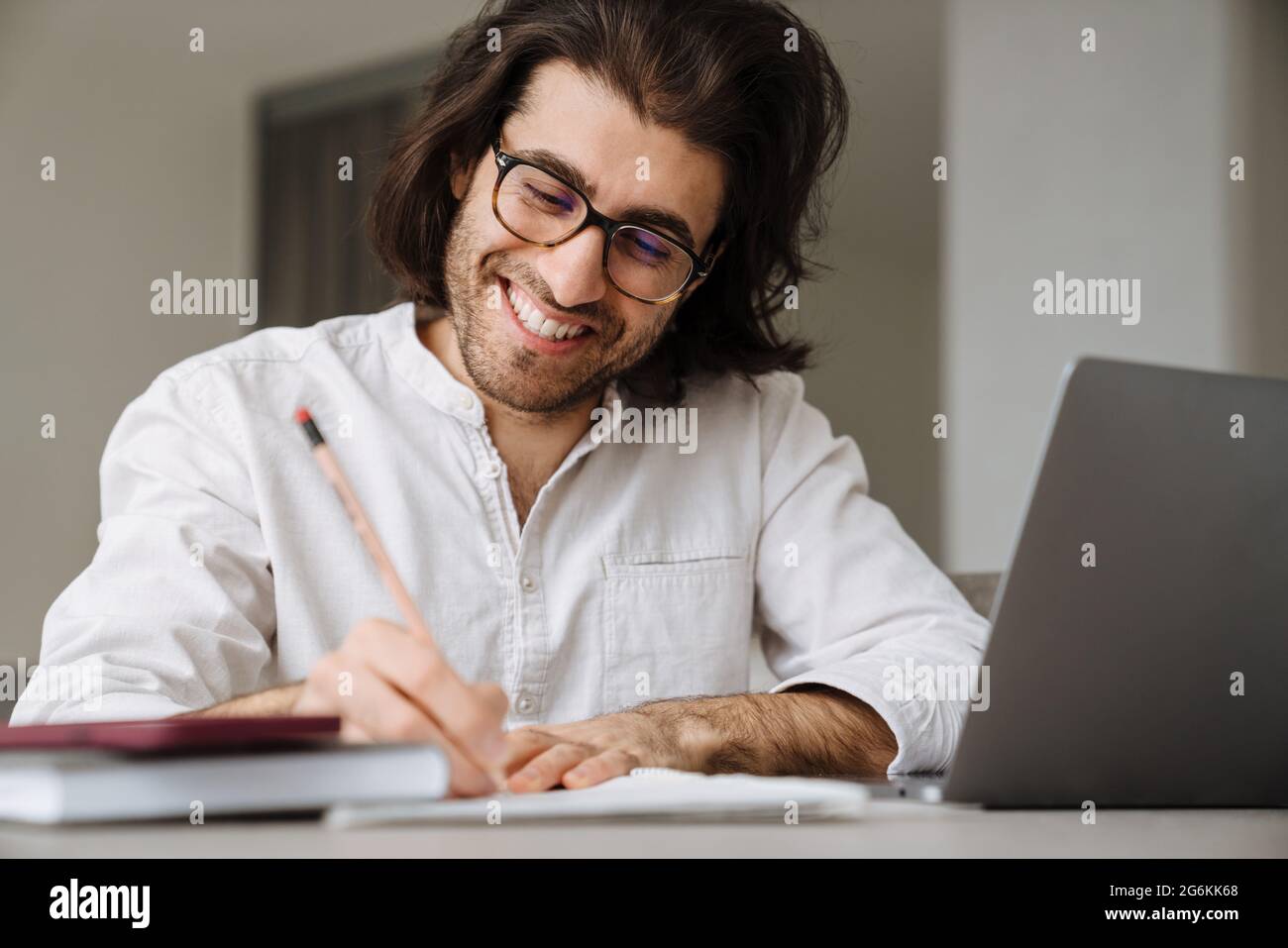 Smiling mid aged brunette turkish man sitting at the table with laptop ...
