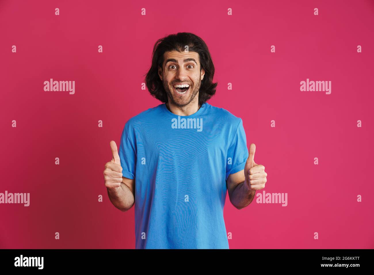 Excited brunette man exclaiming and gesturing thumbs up isolated over ...