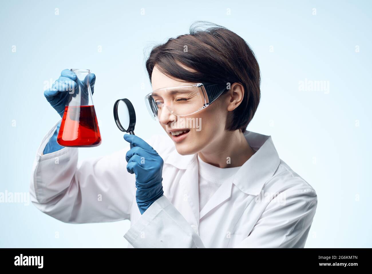 female laboratory assistant looking through a magnifying glass at a ...