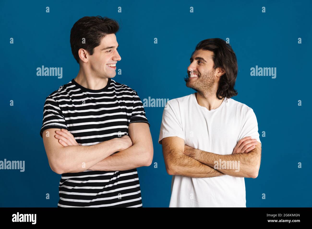 White happy two men smiling at each other while posing with arms ...