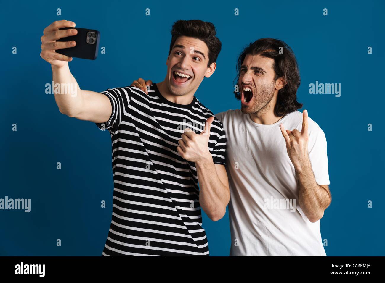 White excited two men taking selfie on cellphone while gesturing ...