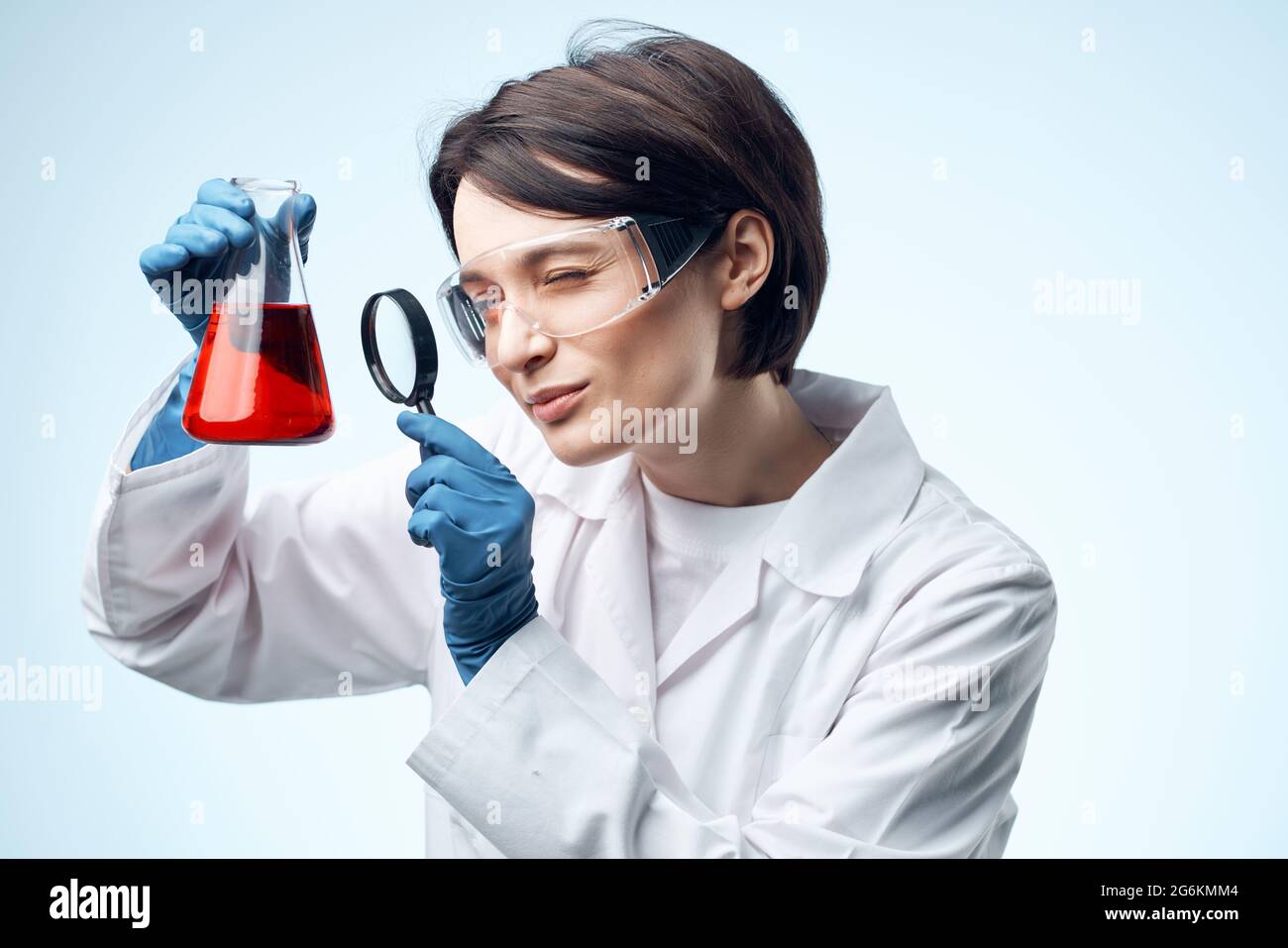 woman scientist looking through a magnifying glass at a chemical ...