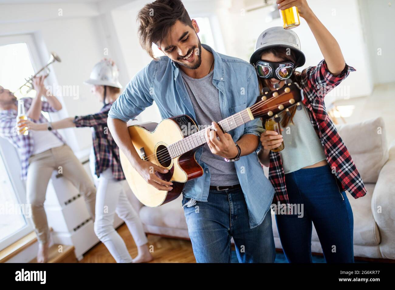 Cheerful friends playing on music instruments and having fun at home ...