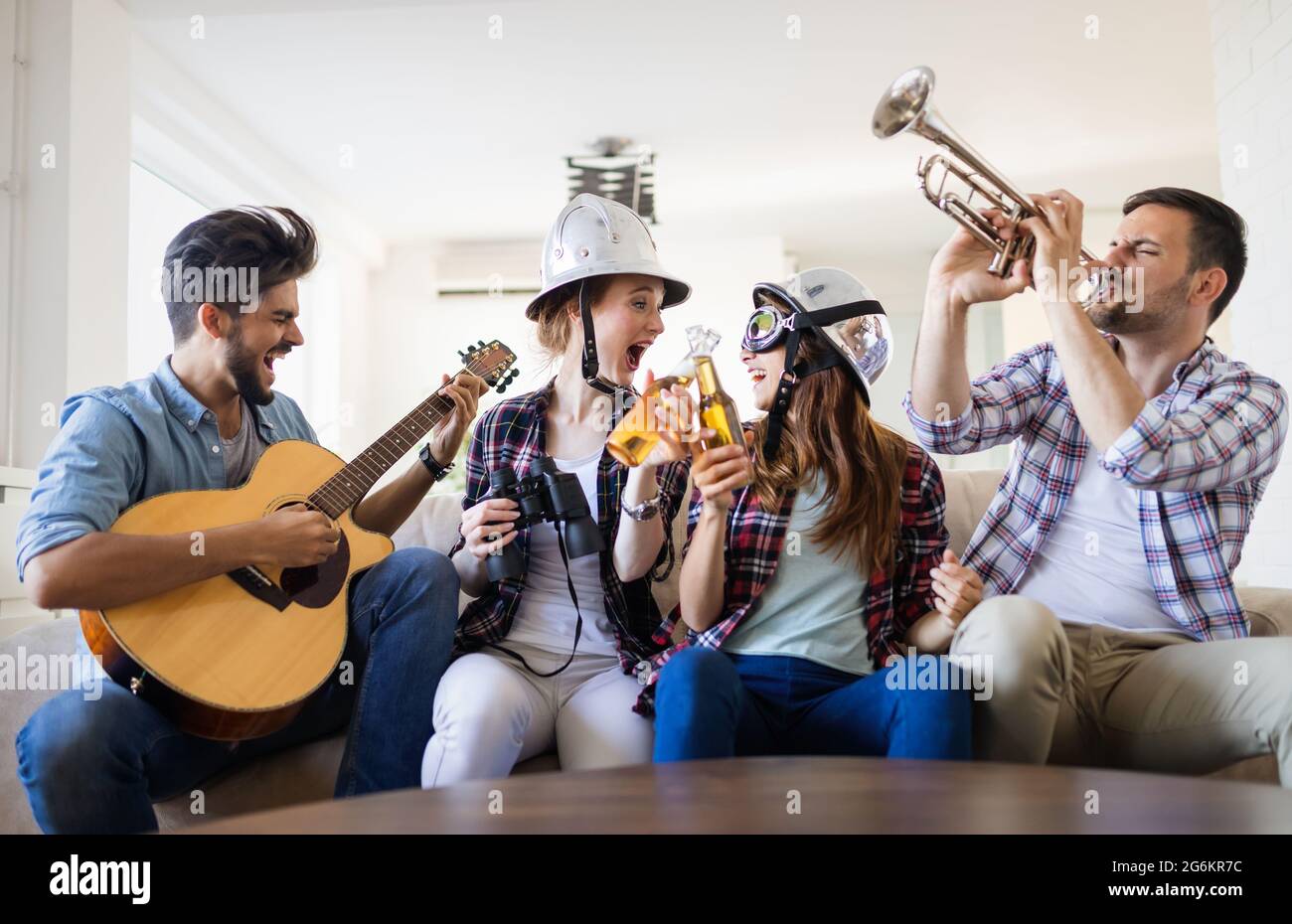 Cheerful friends playing on music instruments and having fun at home ...