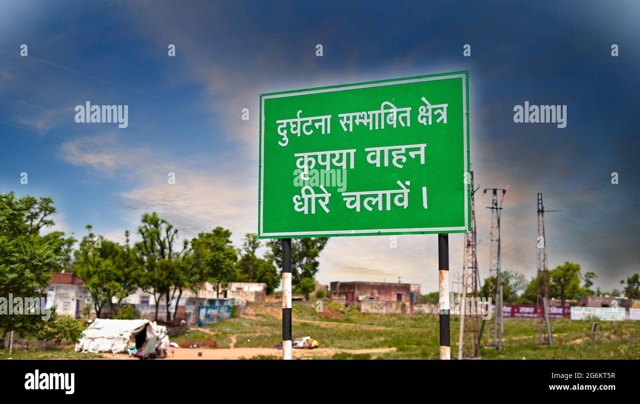 Green sign board with attractive white written language along side road ...
