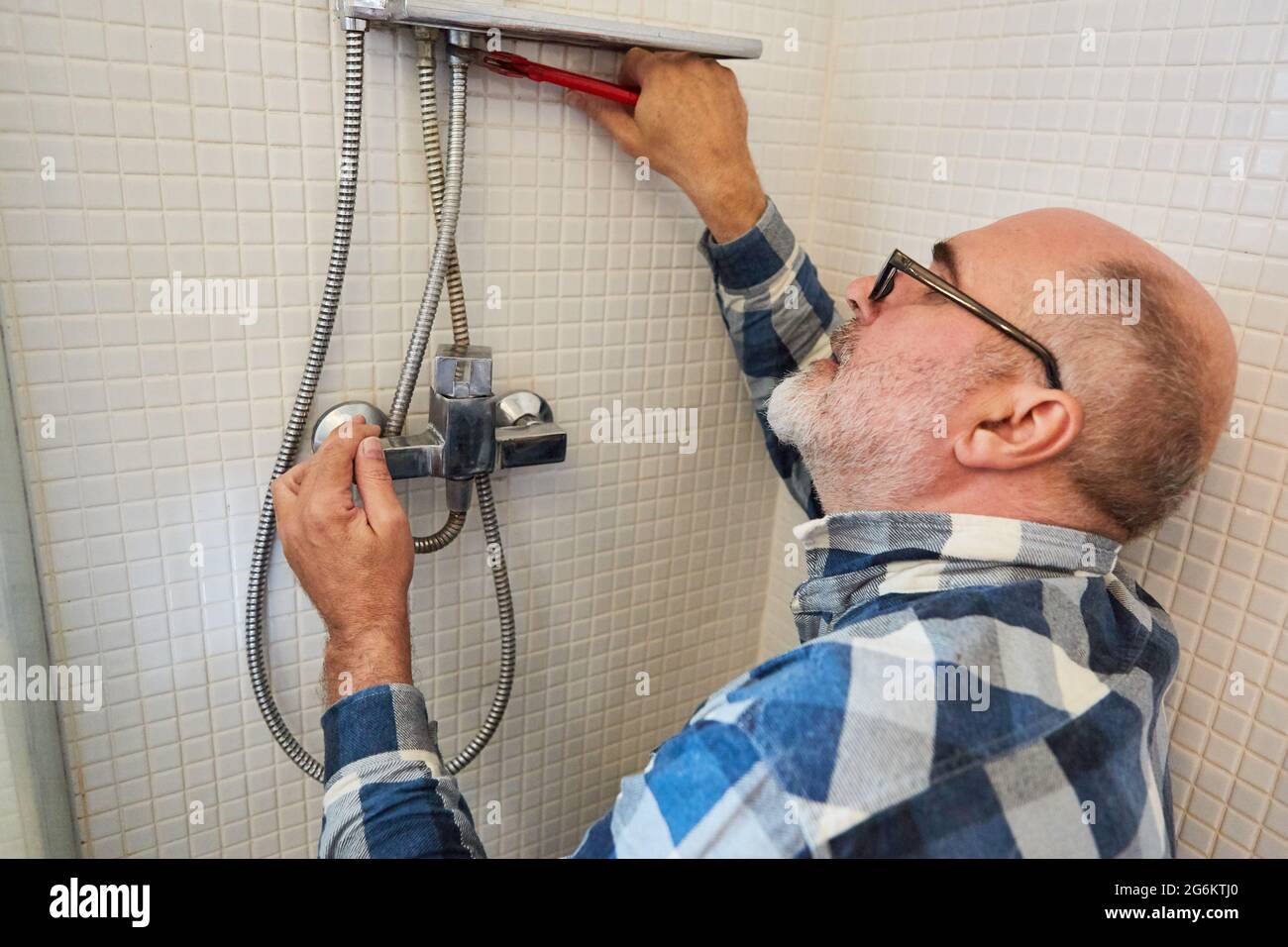 Craftsman plumber repairing broken hose in the shower in the bathroom ...