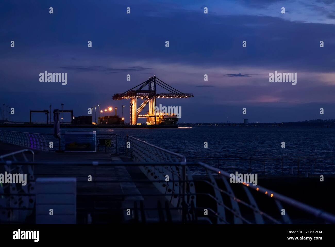 Night promenade by the sea overlooking the illuminated cranes in the ...