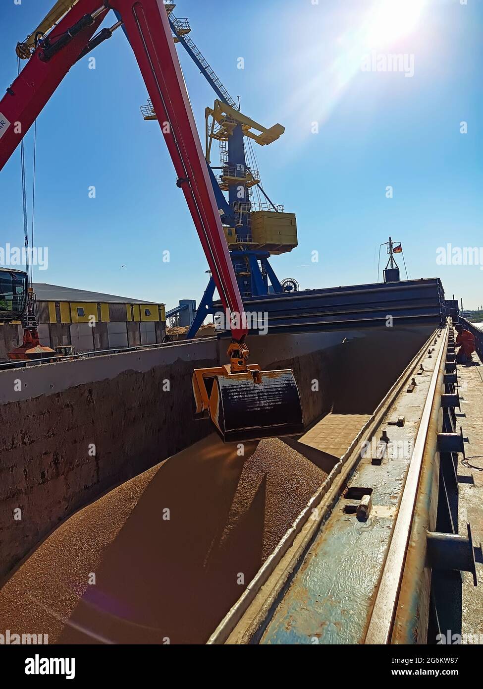 a crane with a manipulator bucket loads wheat onto a dry cargo ship at ...