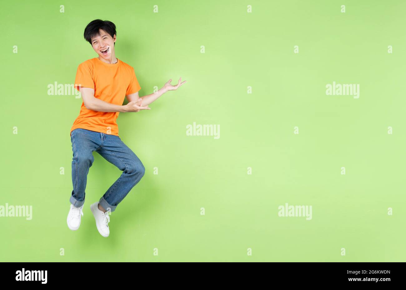 young asian man jumping , isolated on green background Stock Photo - Alamy