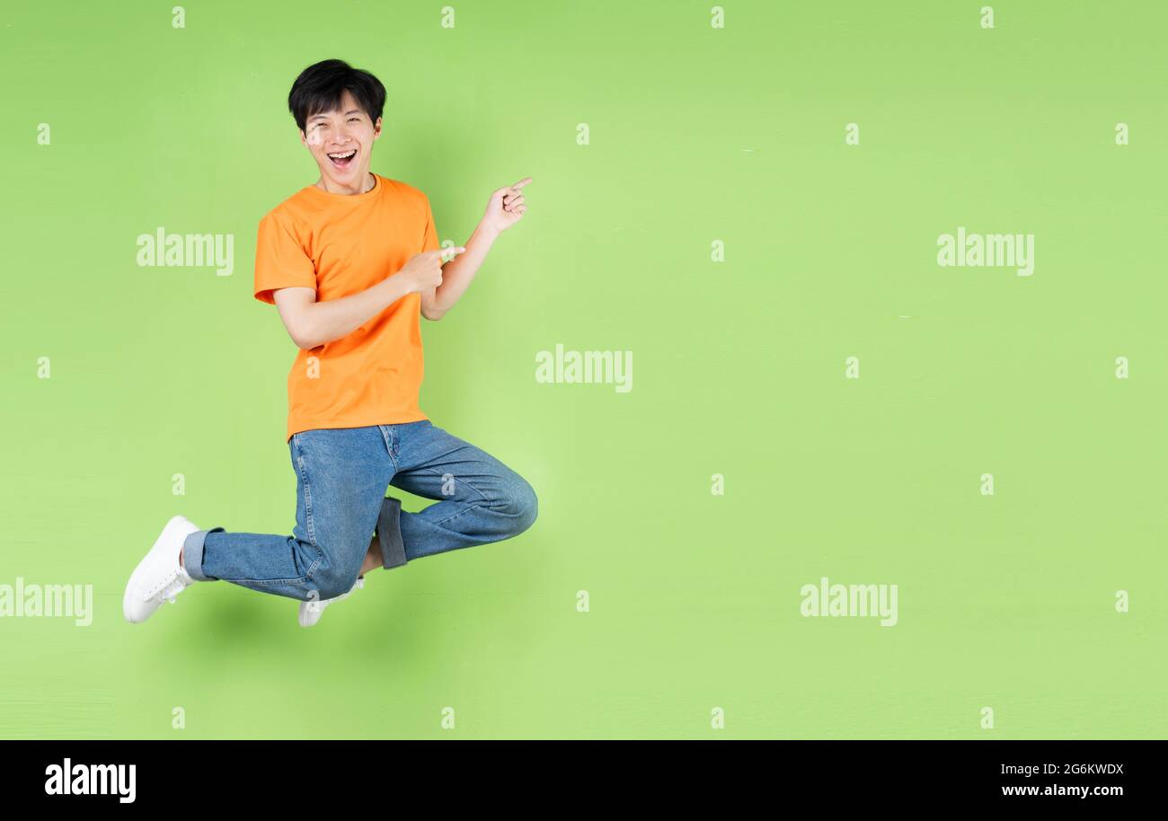 young asian man jumping , isolated on green background Stock Photo - Alamy