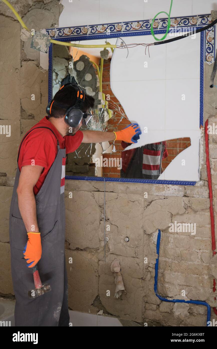 Builder destroying a mirror with a hammer. House renovation Stock Photo ...