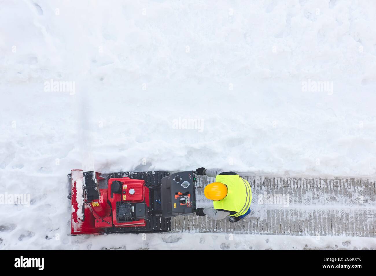 Worker cleaning snow on the sidewalk with a snowblower. Maintenance ...