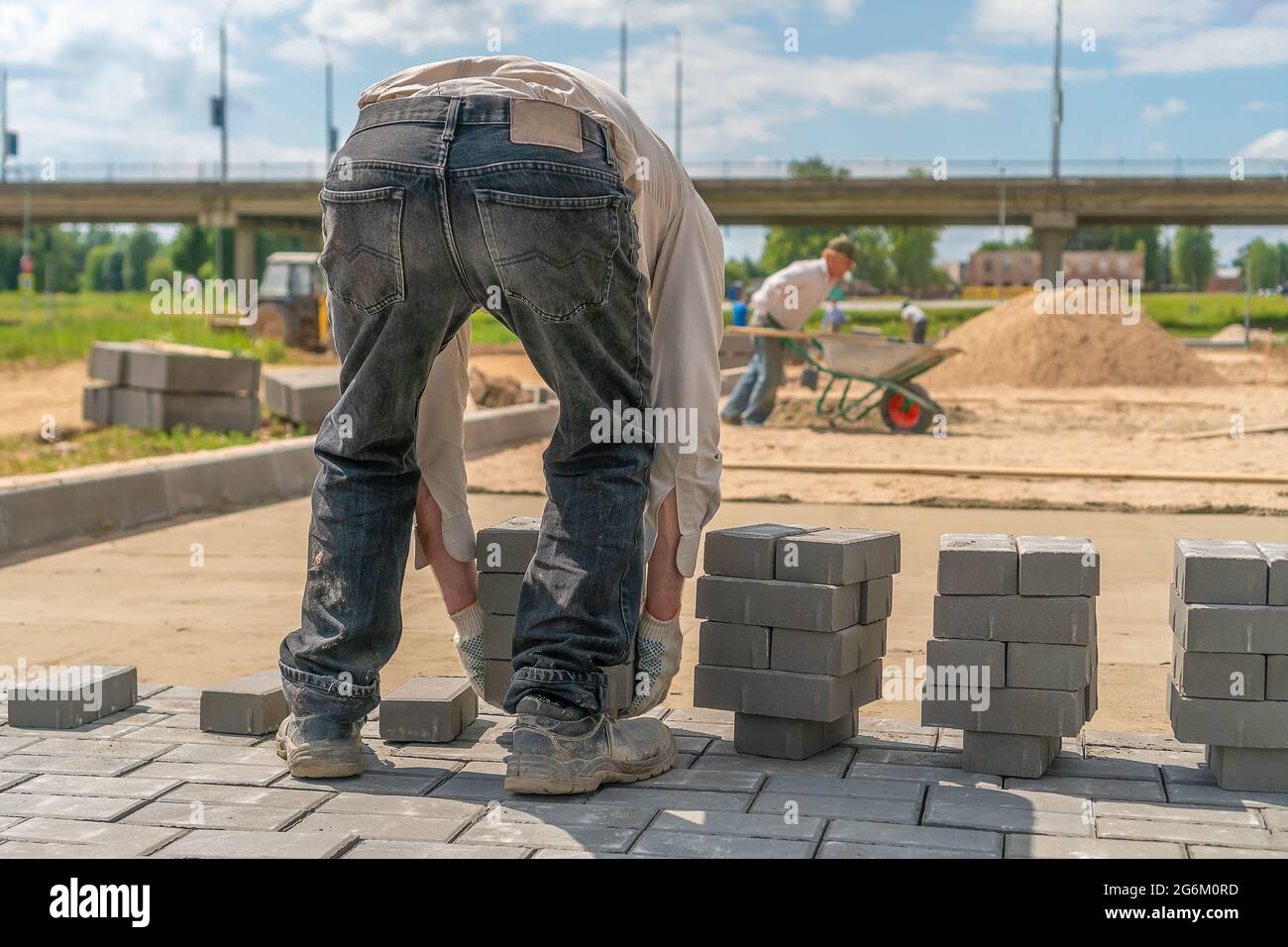 Working man puts a lot of concrete bricks on the ground. Laying of ...