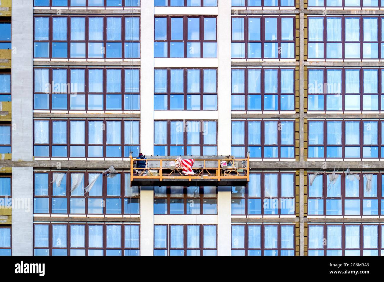 builder in construction cradle works on a building Stock Photo - Alamy