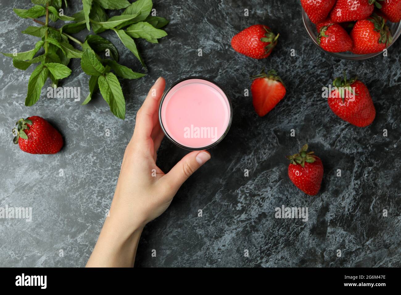 Female hand holding glass of strawberry milkshake on black smokey ...
