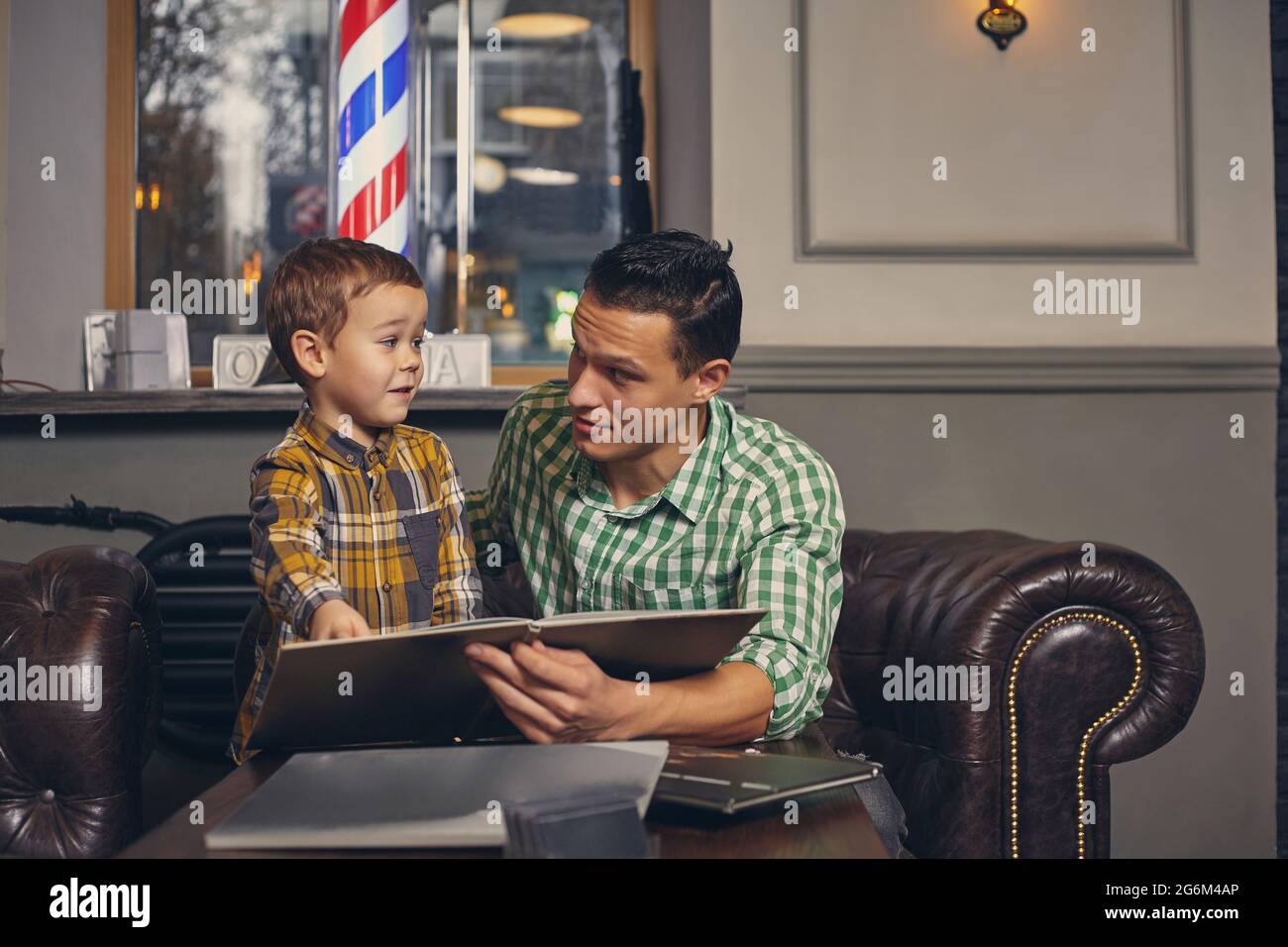 Young father and his stylish little son in the barbershop in the ...
