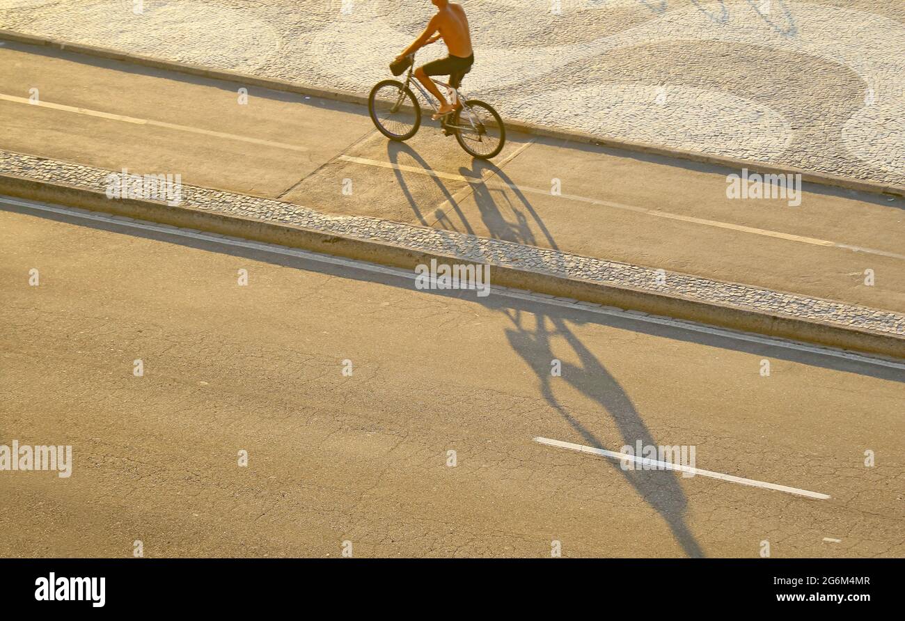 Man cycling along the wave pattern sidewalk of Portuguese pavement ...