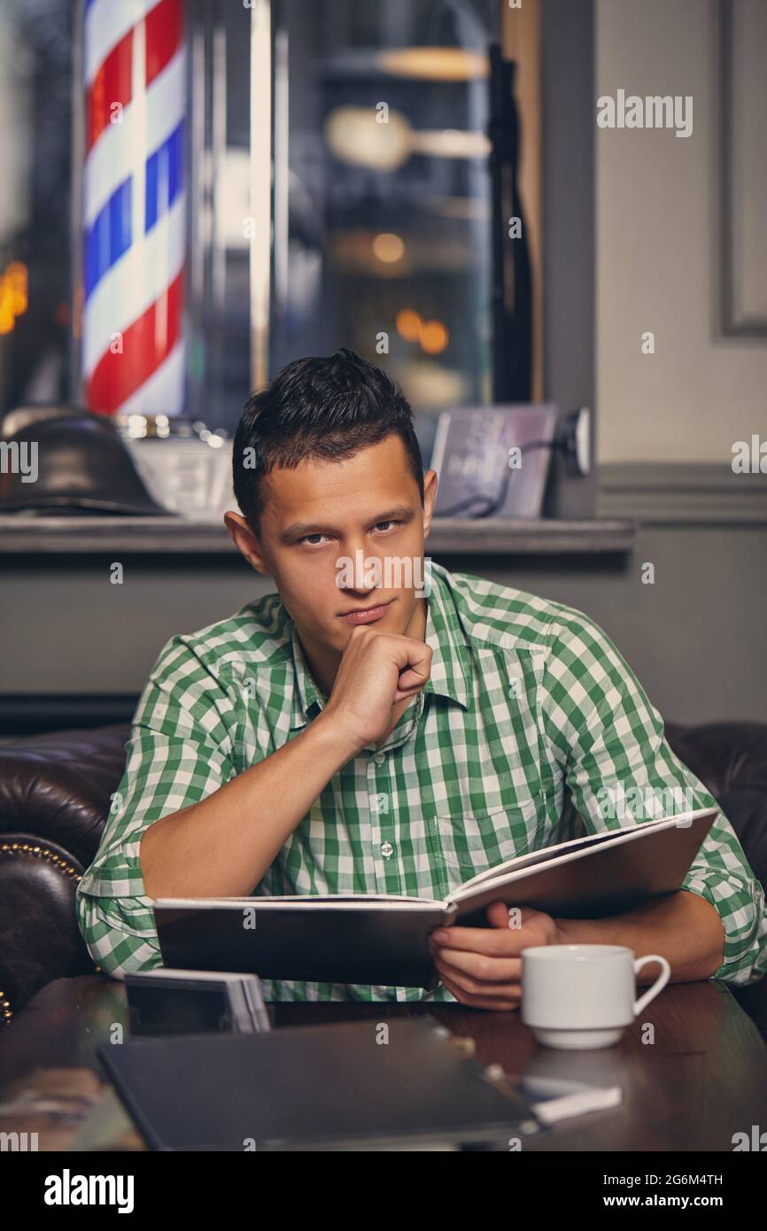 Handsome young man in a barbershop is waiting for the master in the ...