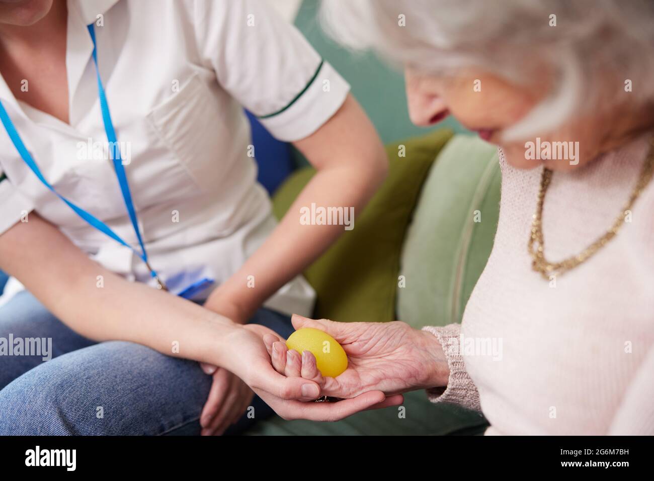 Female Physiotherapist Getting Senior Woman To Squeeze Rubber Ball At ...