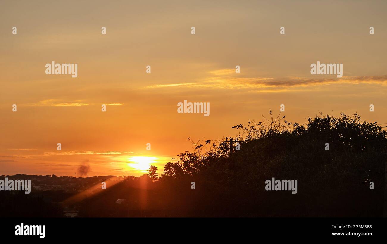 Sunset highlighted by the orange color, with dramatic clouds, below the ...
