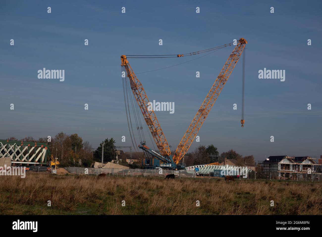 Very large yellow mobile crane with v-shaped booms against a blue sky ...