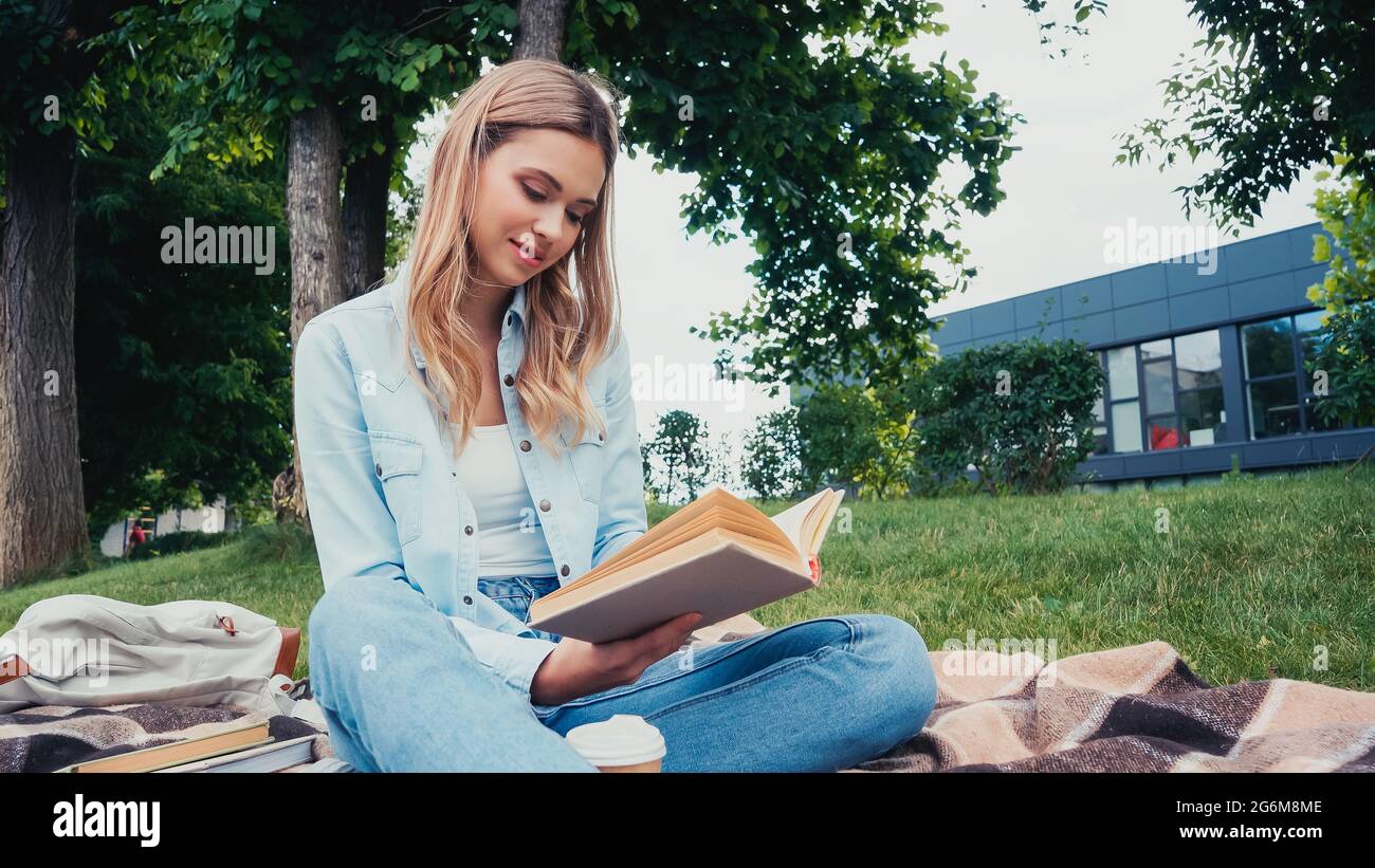 cheerful woman sitting and reading book outside Stock Photo - Alamy