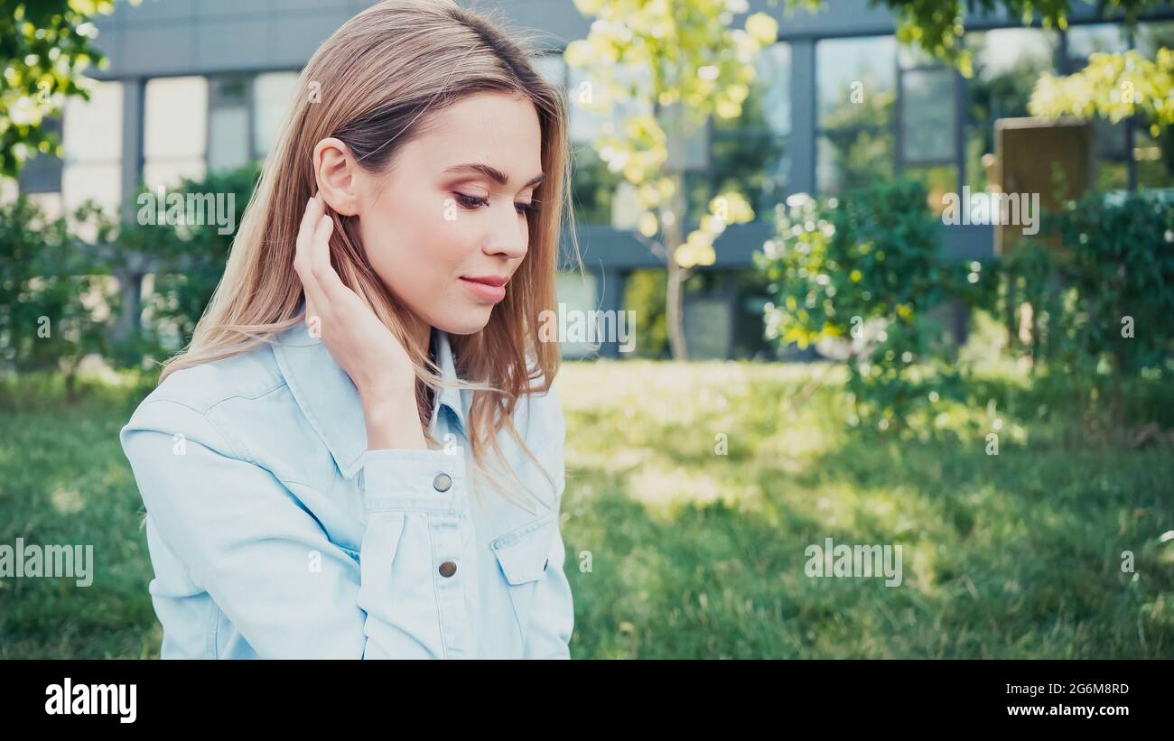 pretty young woman adjusting hair outside Stock Photo - Alamy