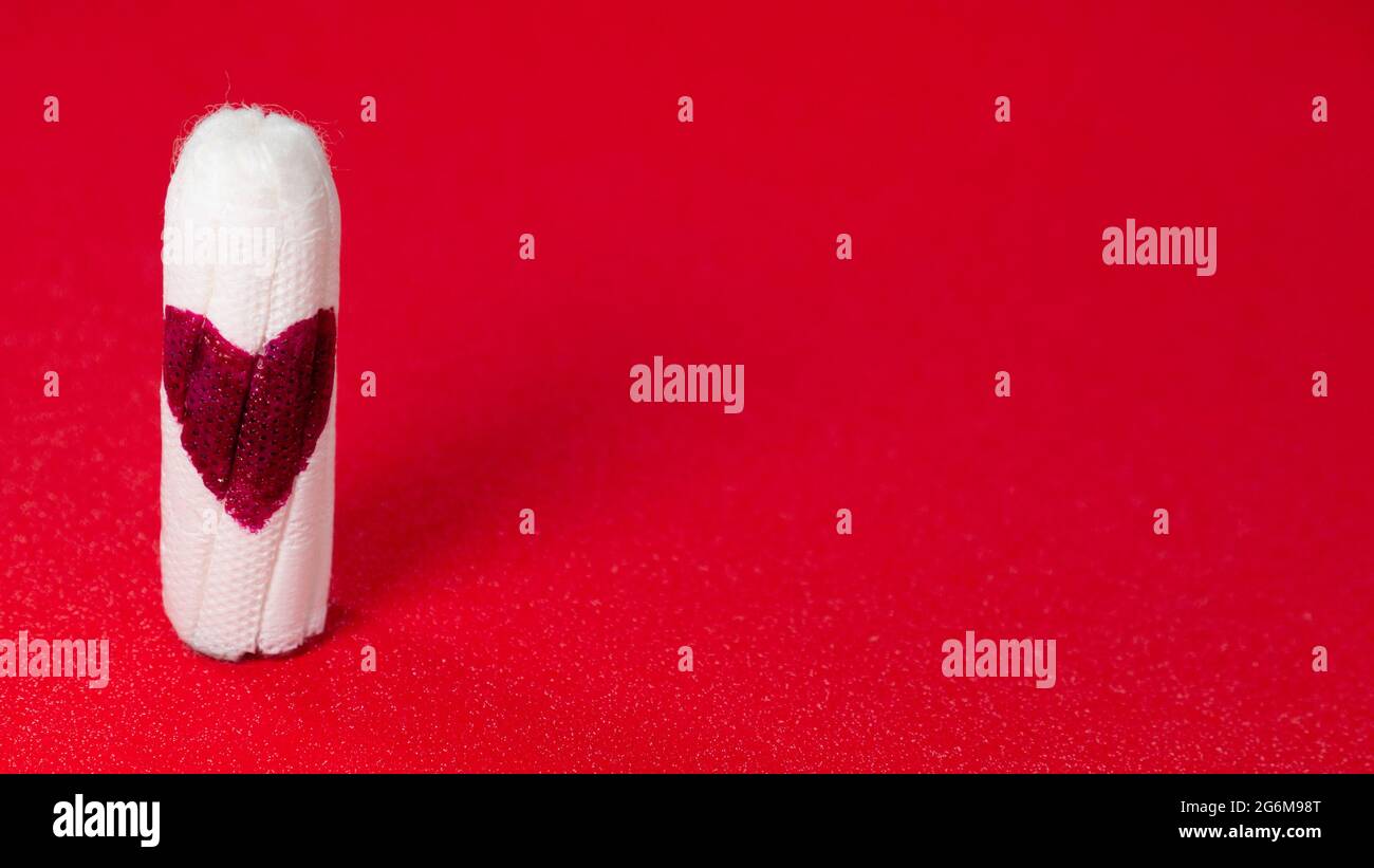 Tampon with heart symbol on red background. Copy space for tex. Female ...