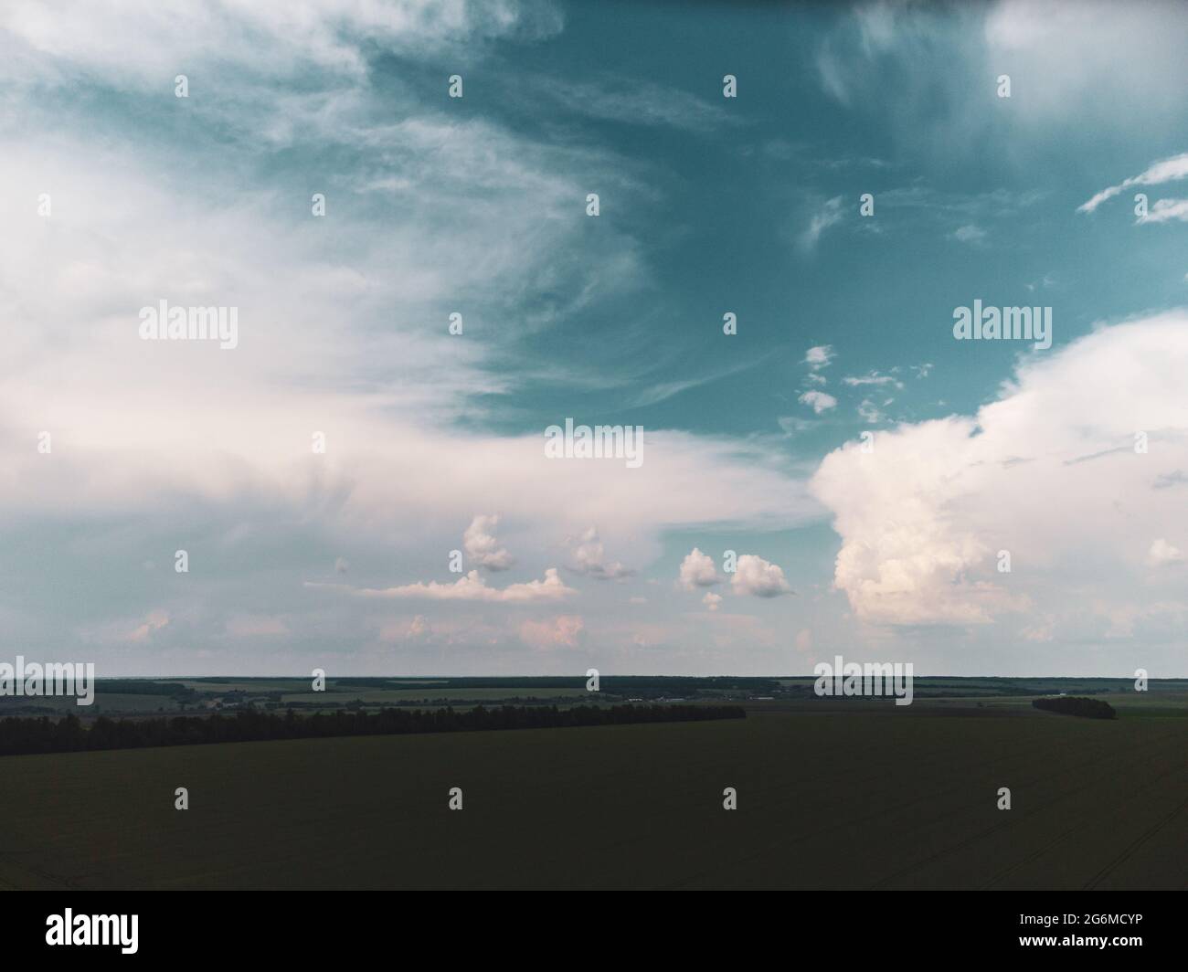 Aerial fly above green fields with stormy cloudscape. Dark rainy scenic ...