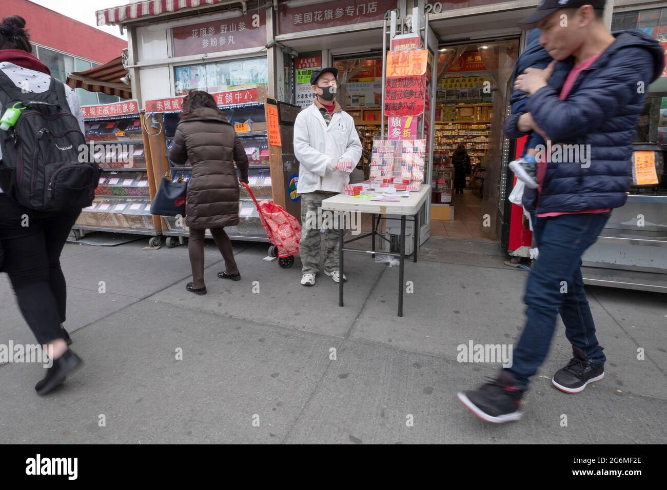 A pre pandemic street scene of a merchant wearing a mask and several ...