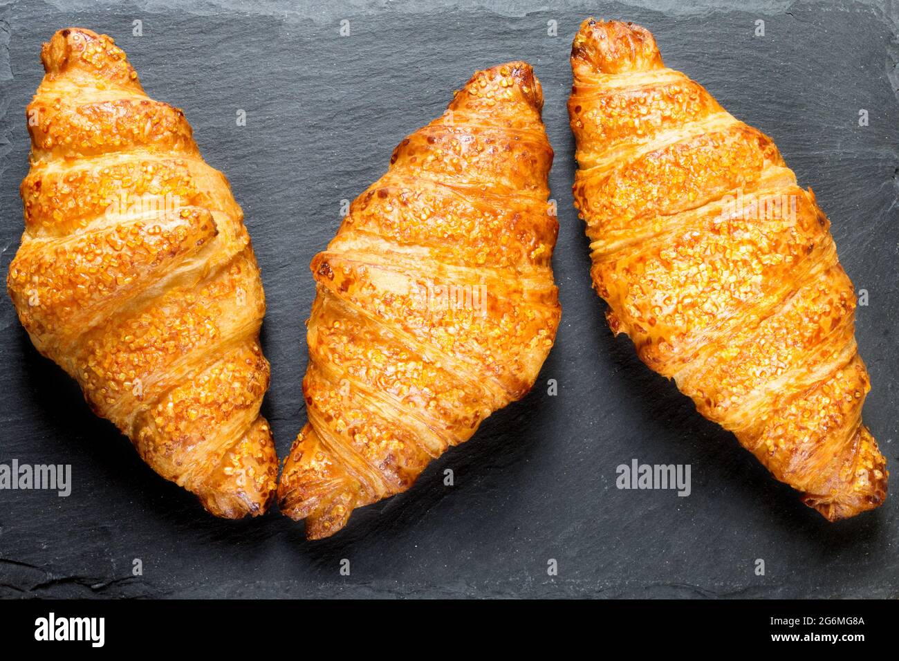 three tasty croissants on black stone background. French food. Close up ...