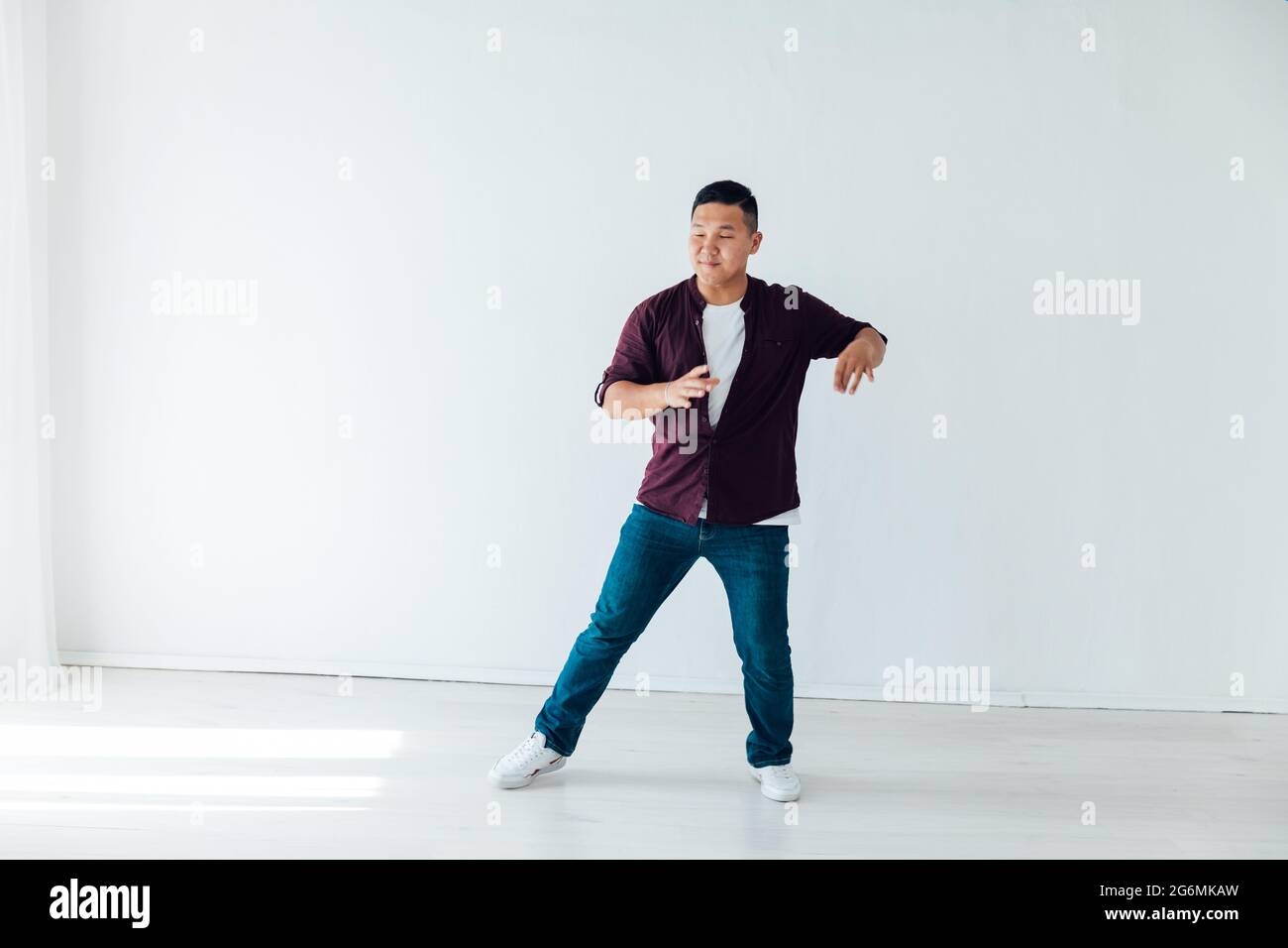 Beautiful Asian man dances to music in white room Stock Photo - Alamy